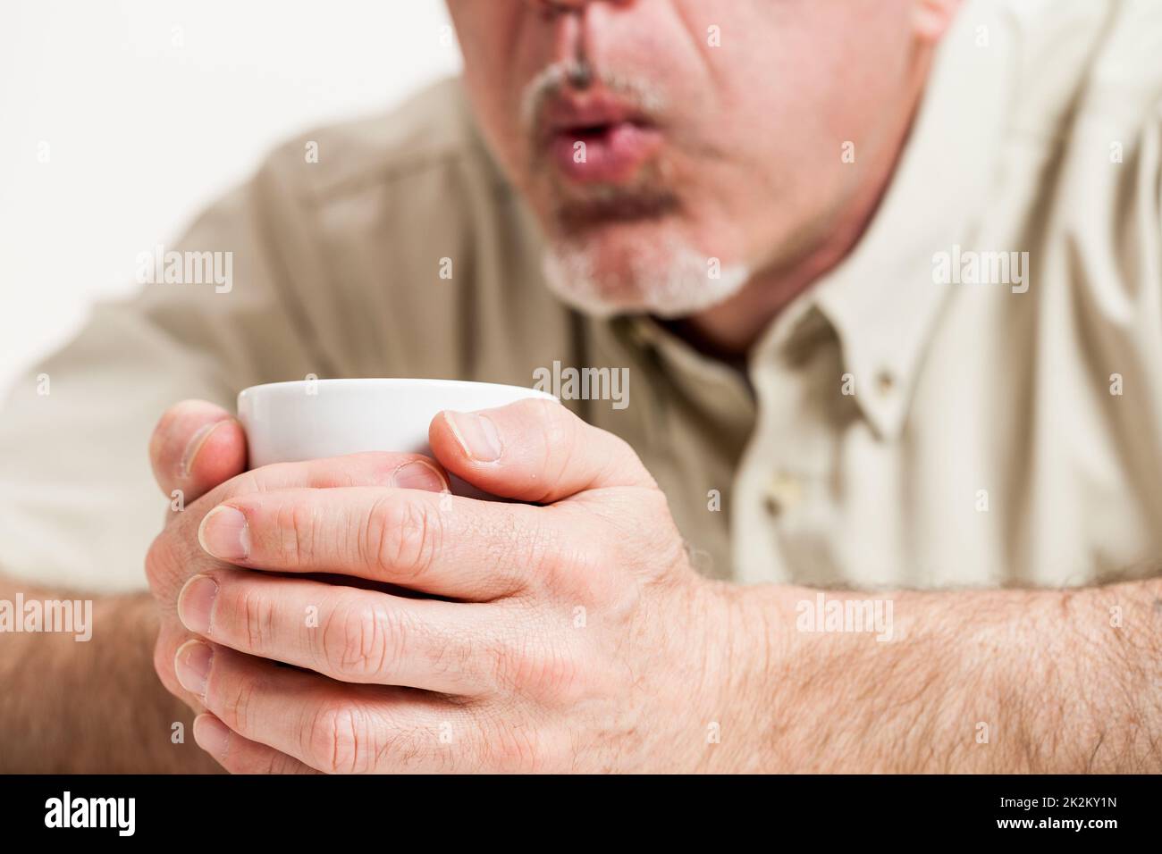 Cropped head and shoulders of man blowing into cup Stock Photo - Alamy