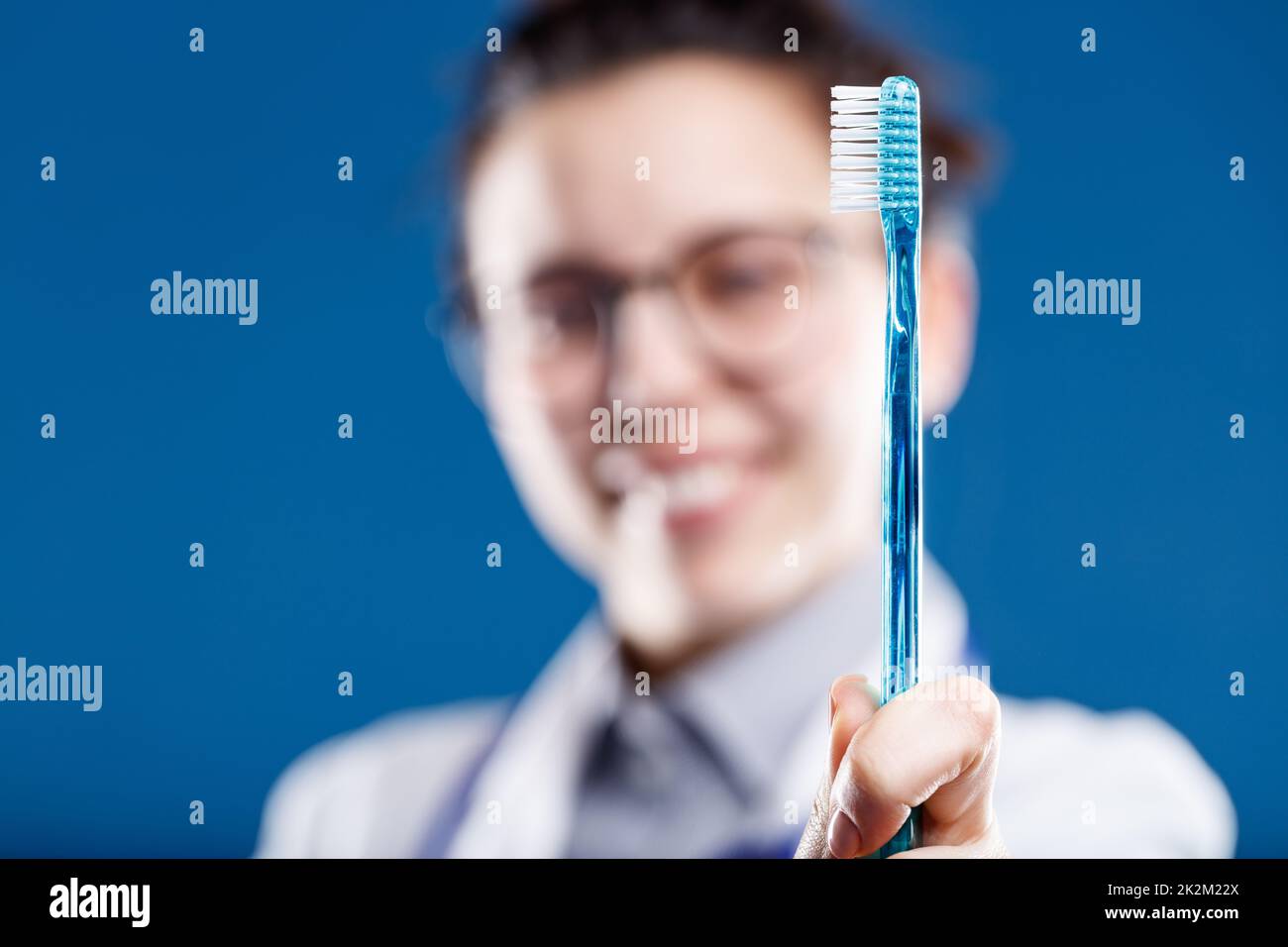 brush your teeth! smiling dentist shows toothbrush Stock Photo - Alamy