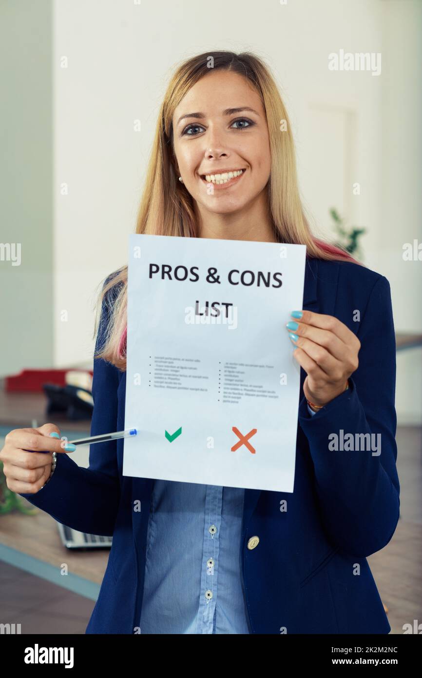 Smiling businesswoman holding up a Pros and Cons list Stock Photo - Alamy