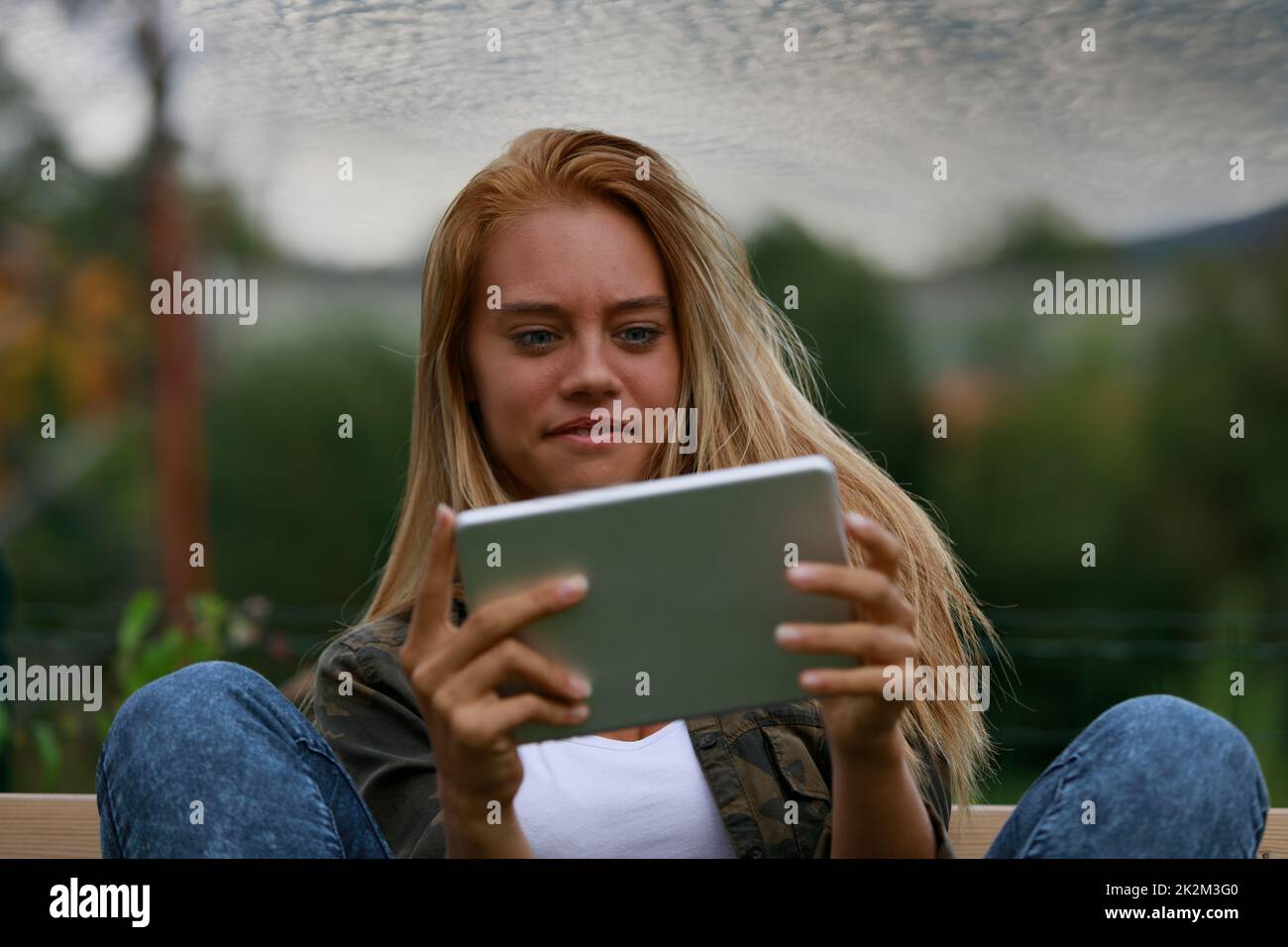 Shocked young woman looking at her tablet in scepticism Stock Photo - Alamy
