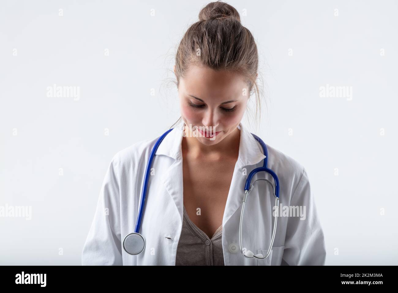 front portrait of young female doctor looking down with a slight smile ...