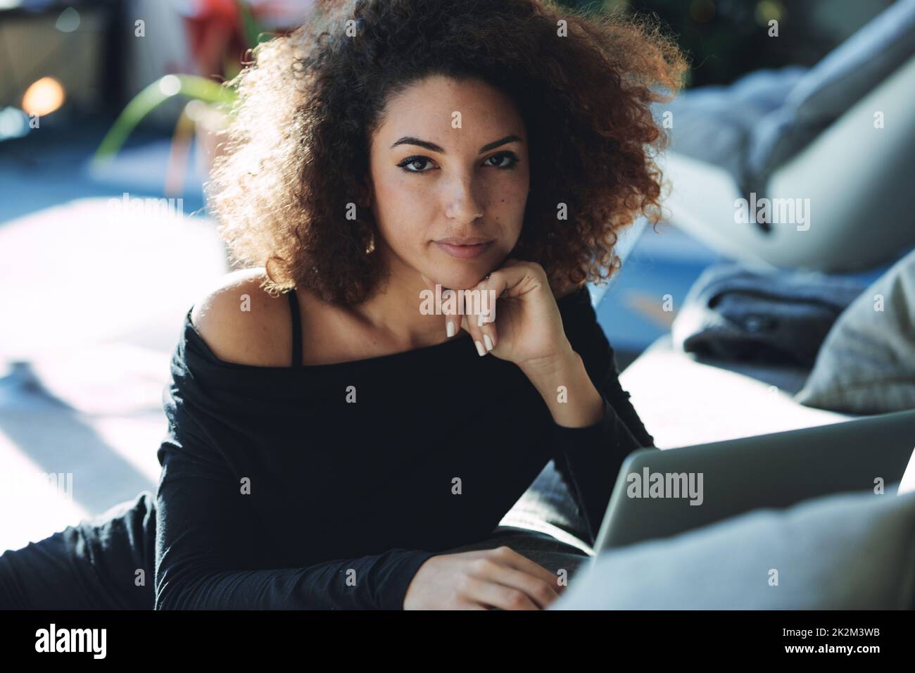 Young woman working on a laptop looking thoughtfully at camera Stock ...