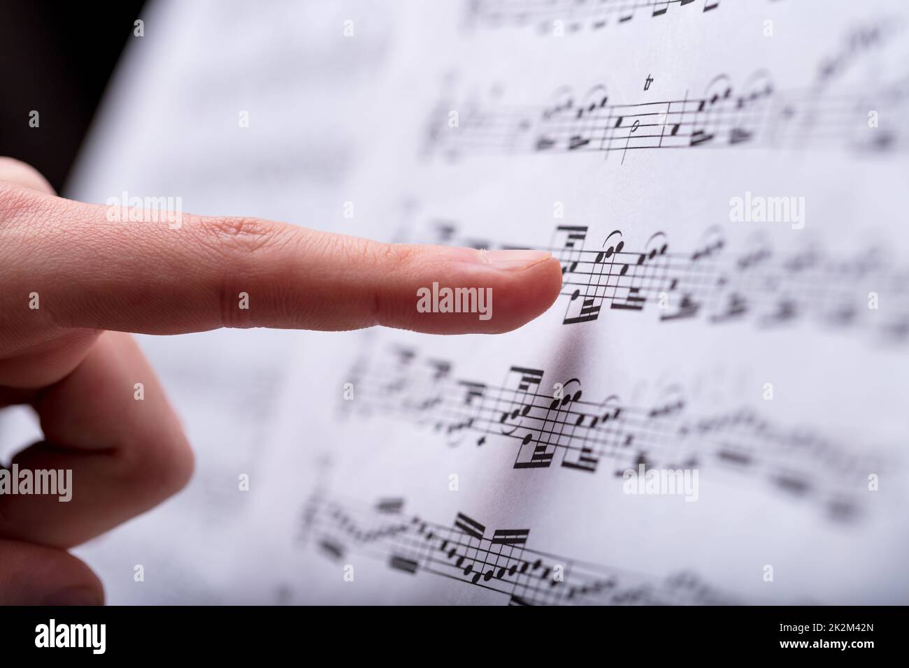 notes on a musical score spotted by finger Stock Photo - Alamy
