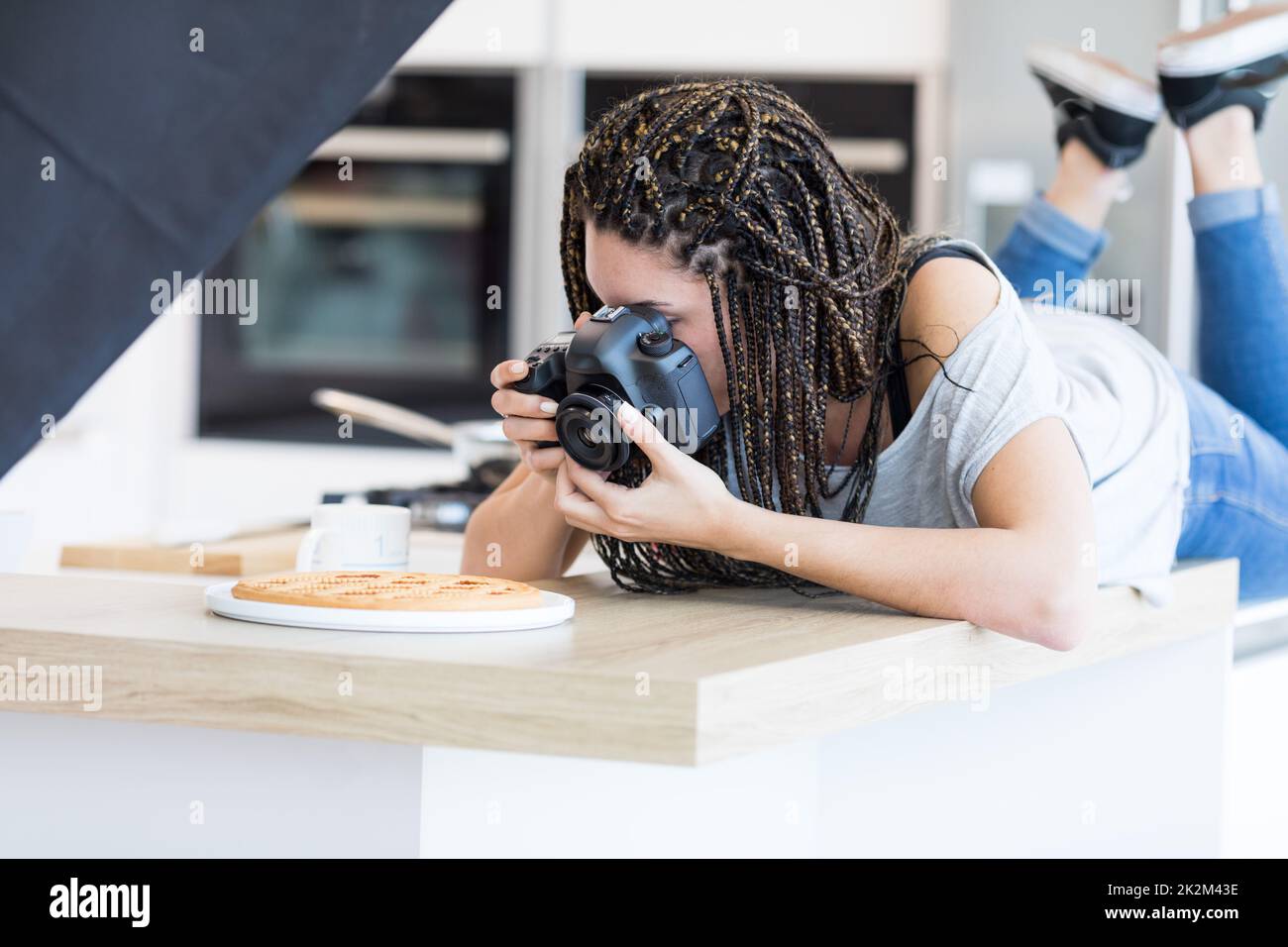 Girl lying on table and photographing pizza Stock Photo - Alamy
