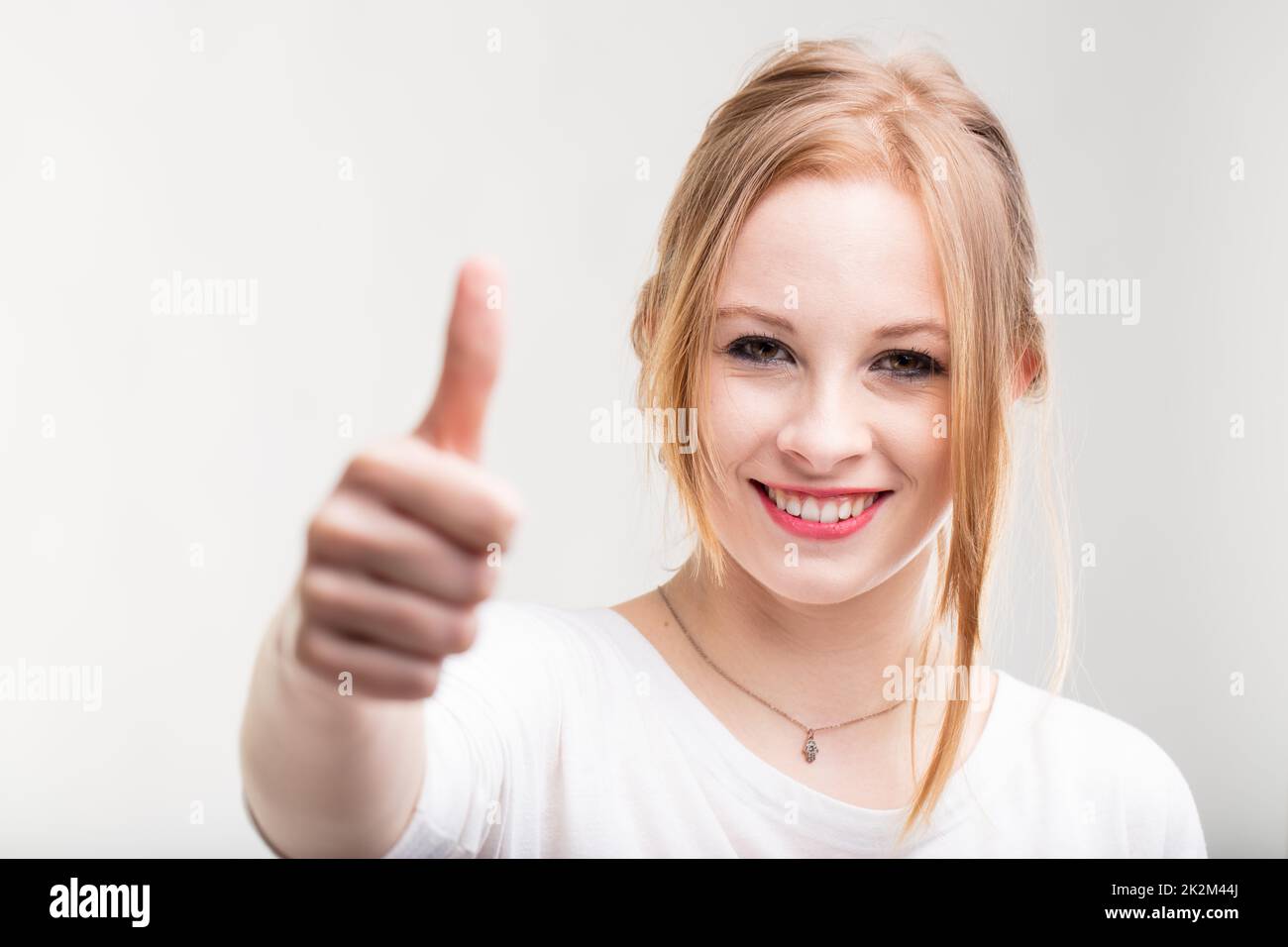 Smiling young woman giving a thumbs up Stock Photo - Alamy