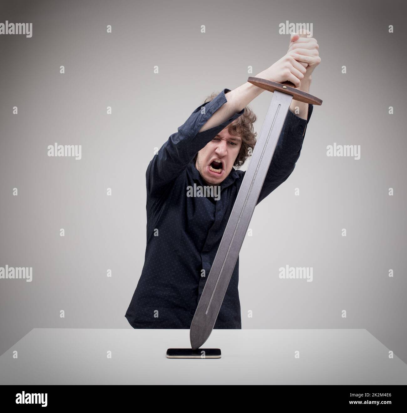 angry man hitting his phone with a sword Stock Photo - Alamy