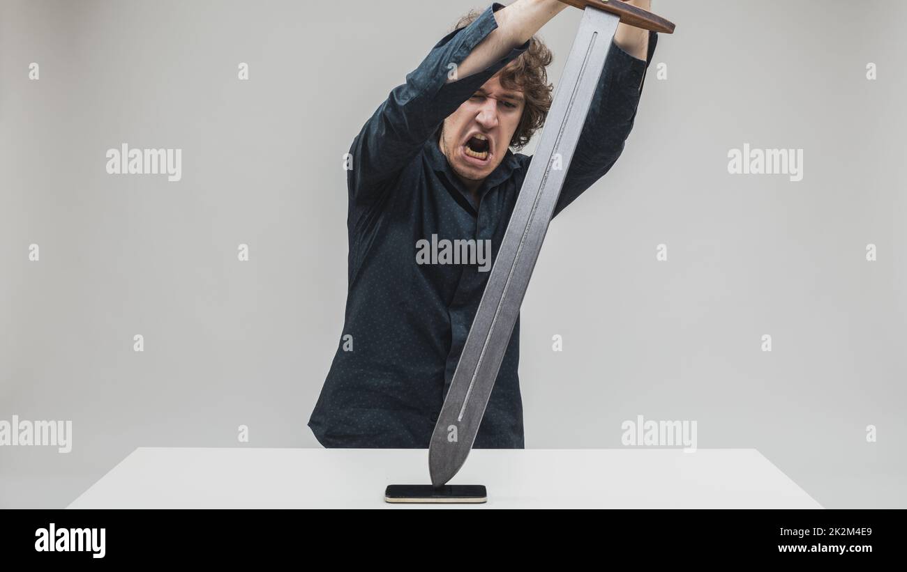 angry man hitting his phone with a sword Stock Photo - Alamy