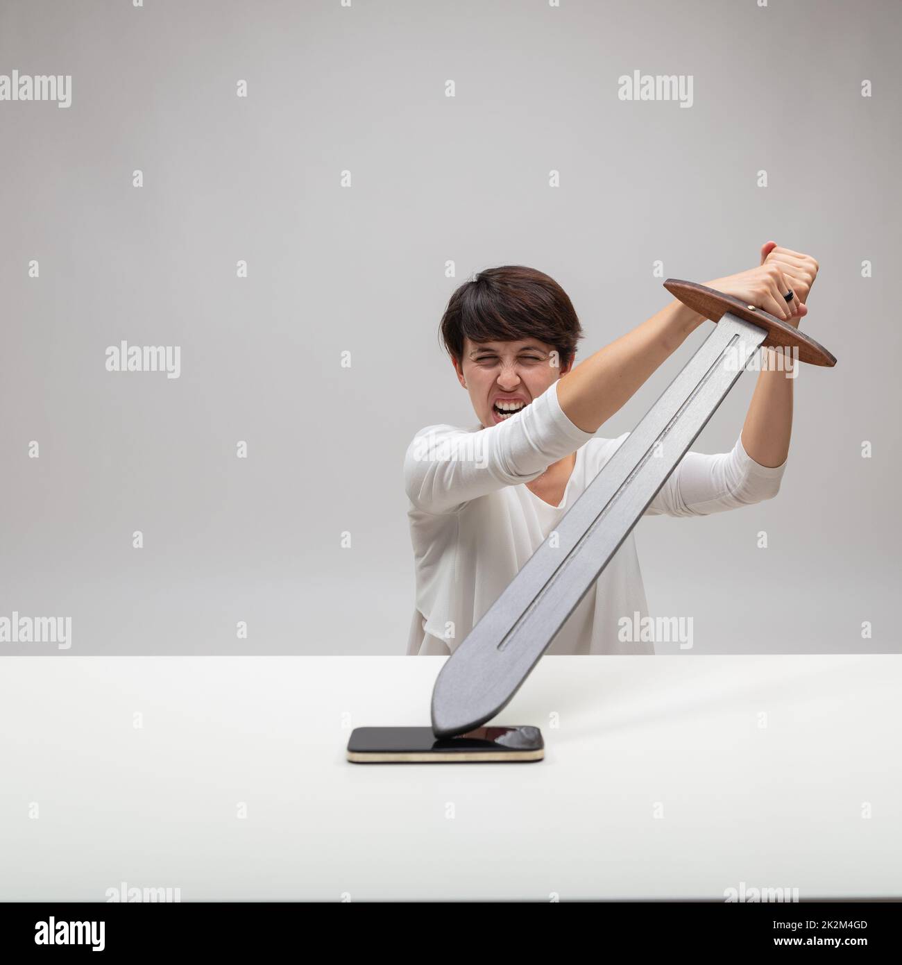 Angry woman attacking her mobile with a sword Stock Photo - Alamy