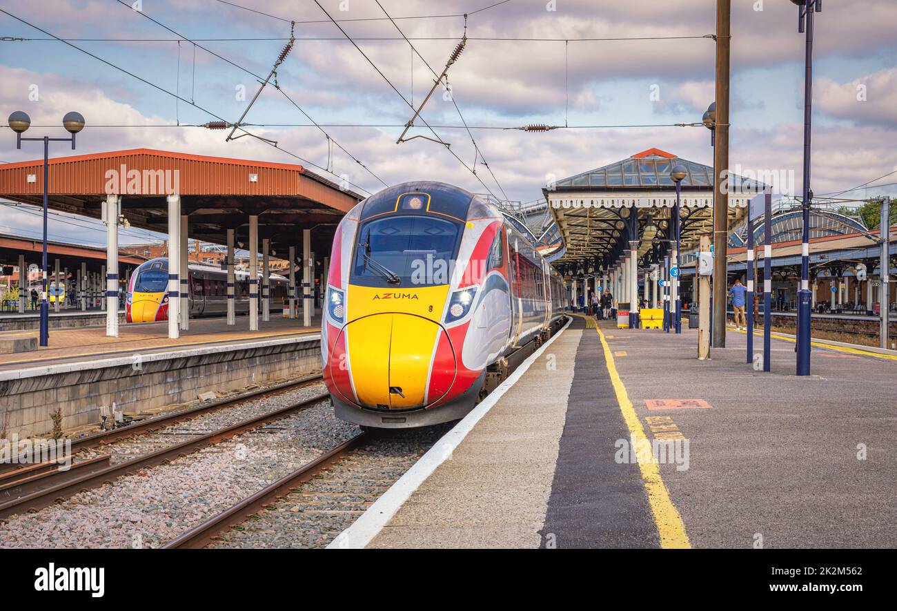 A train rests at a platform with a historic canopy. Another train is in ...