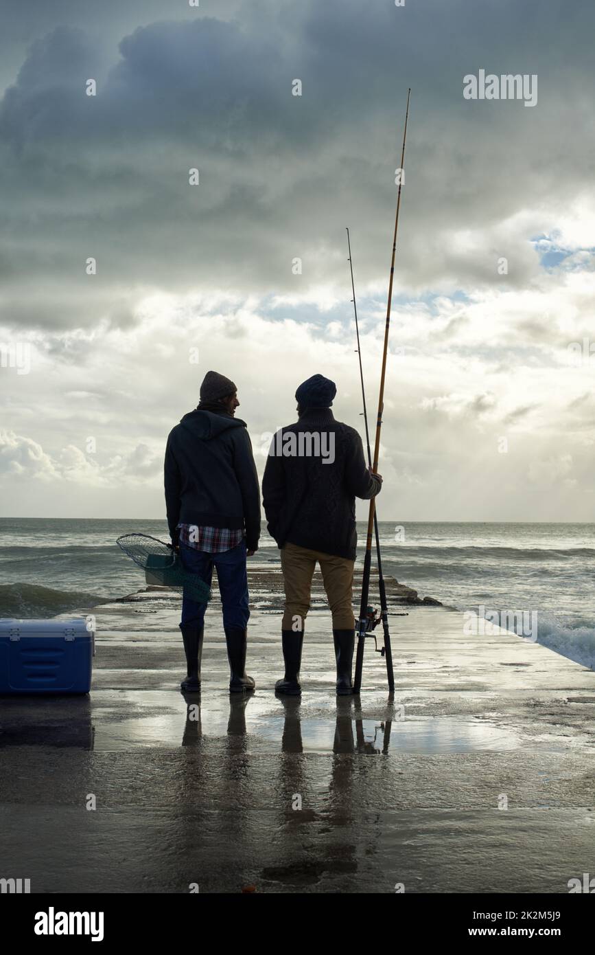 Its been a great day.... Full length shot of two young men fishing at ...