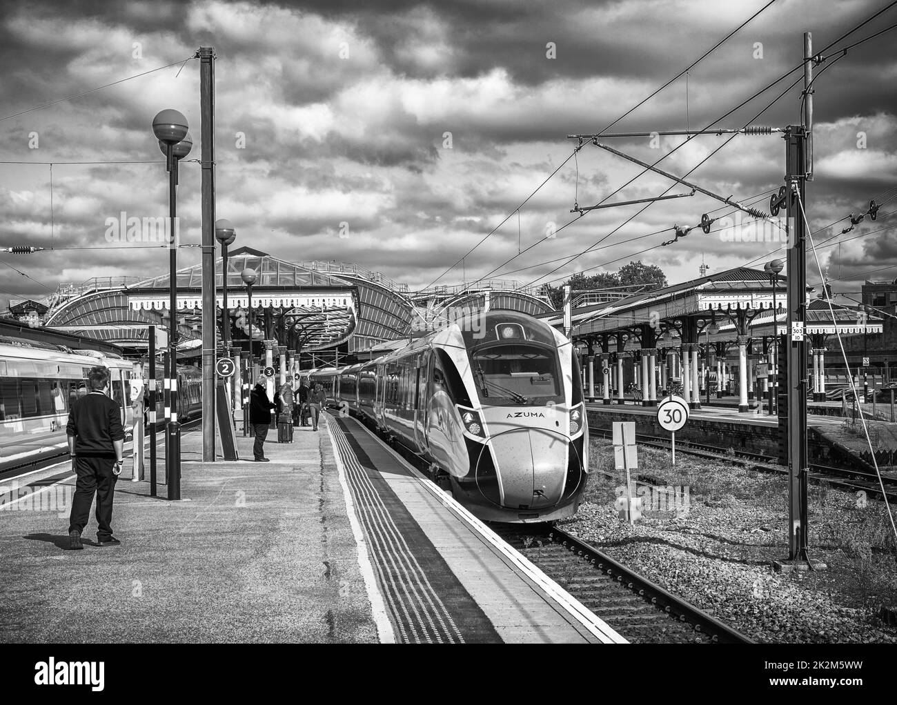 A train rests at a platform with a historic canopy. Crew members and ...