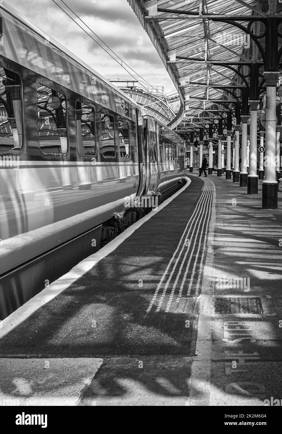 The carriages of a train rests beside a platform with a historic canopy ...