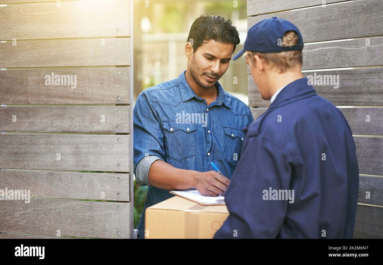 Signing for his package. a young man receiving a package at home Stock ...