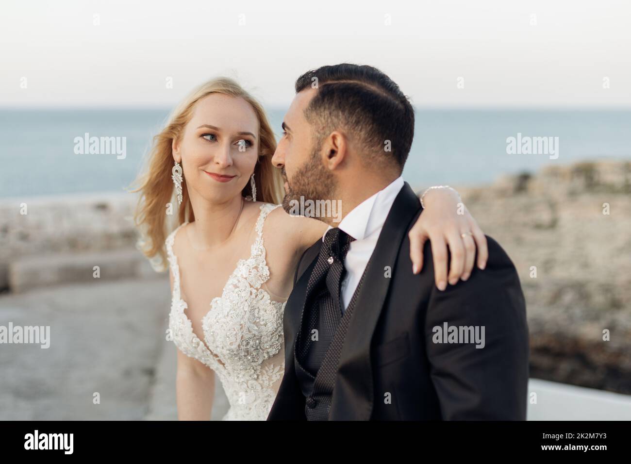 Portrait of couple sitting on ancient bridge, meeting eyes. Young woman ...