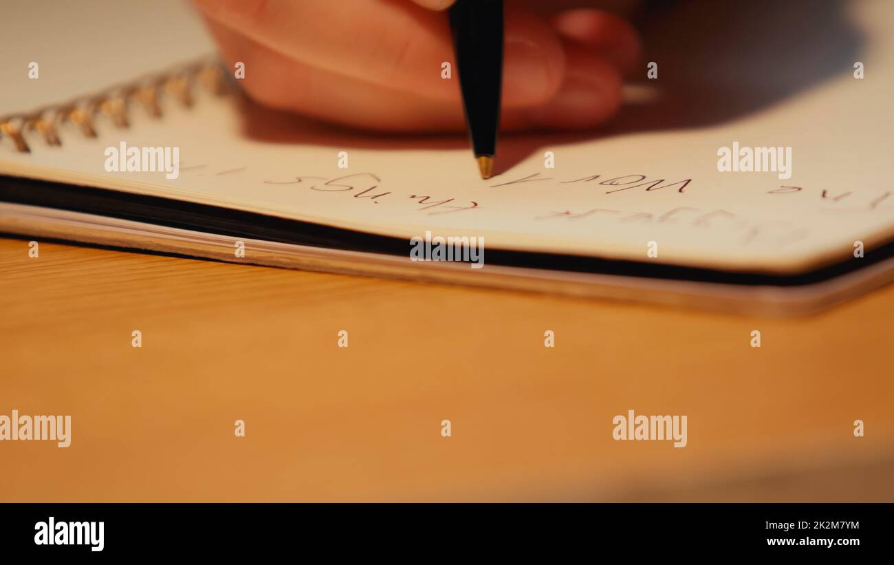 partial view of man holding pen while writing on notebook,stock image ...