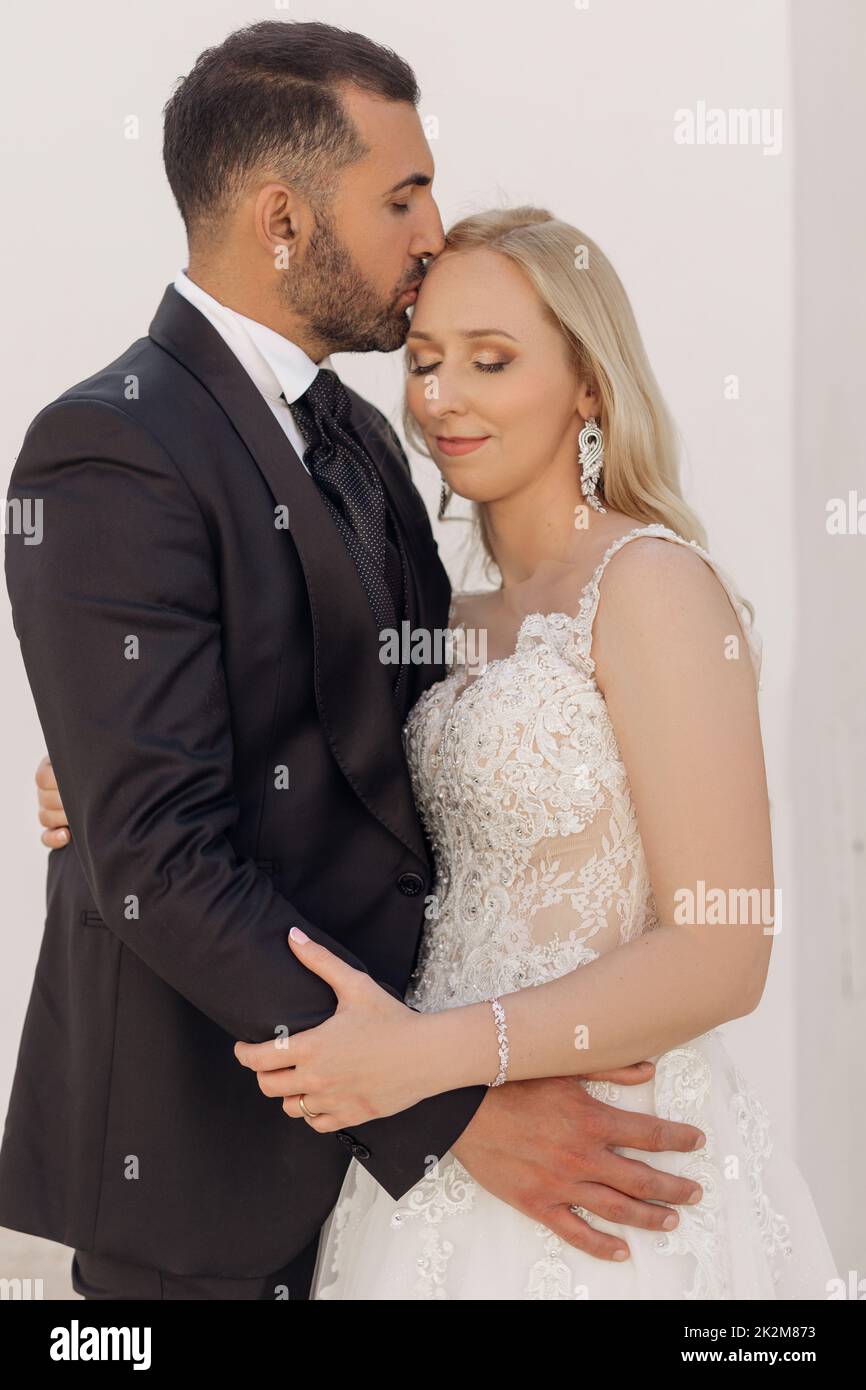 Portrait of blissful wedding couple standing on street with closed eyes ...
