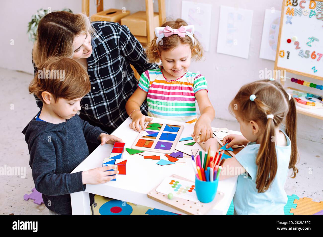 Little kids and educator studying, folding cubes and paper geometric ...