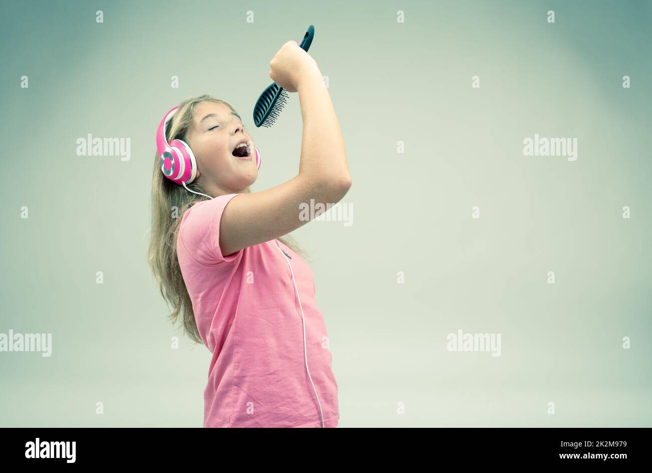 Cute young girl singing along to her music Stock Photo - Alamy