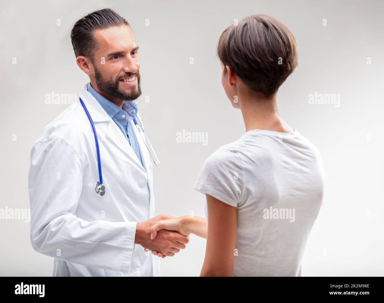 Smiling male doctor shaking hands with a patient Stock Photo - Alamy