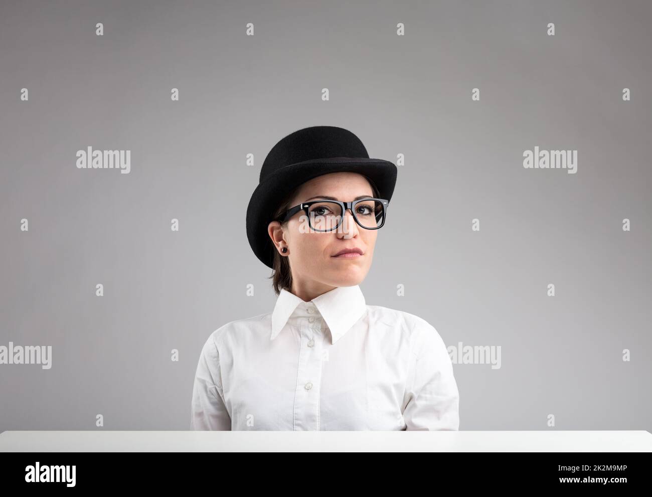 serious woman in bowler, glasses and white shirt Stock Photo - Alamy