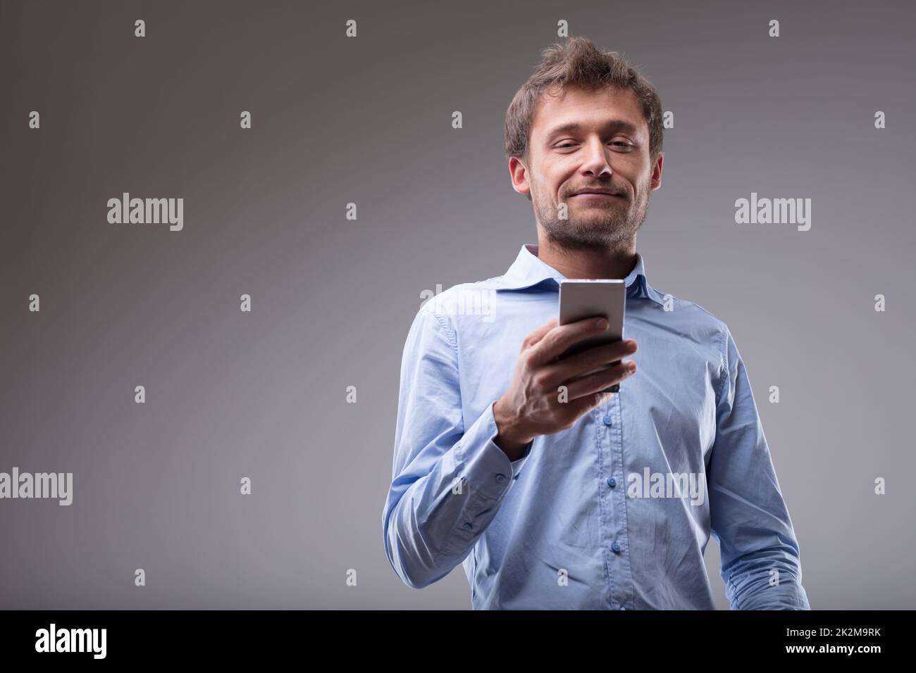 Young man reading a text message on his cellphone Stock Photo - Alamy