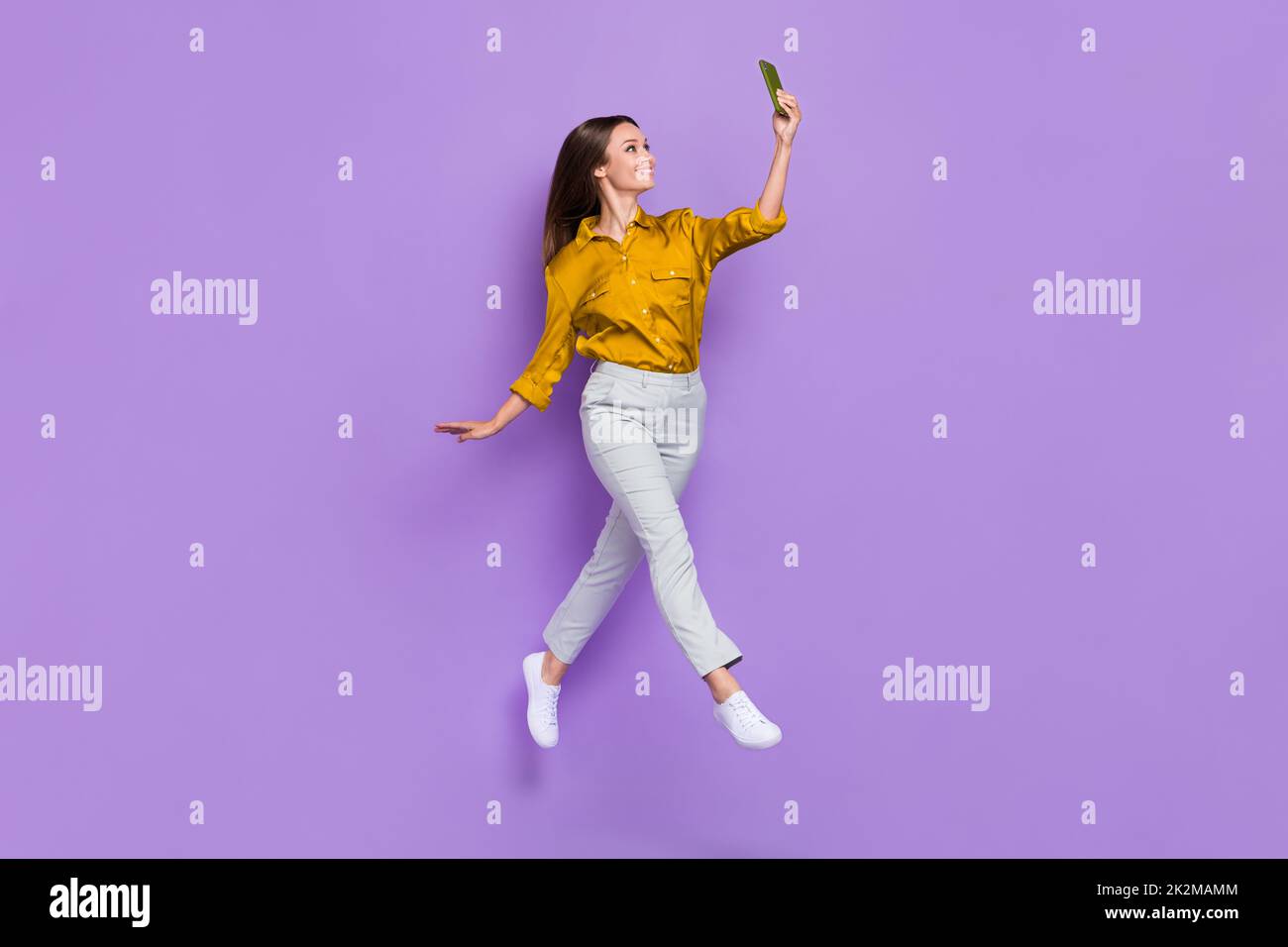 Full size photo of energetic cheerful girl jump hold telephone take ...