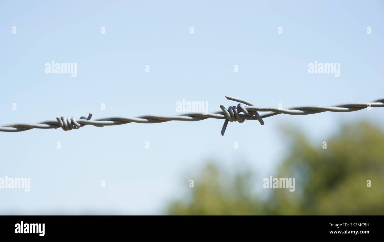Barbed wire against blue sky. Part of guarding farm fence. A close up ...
