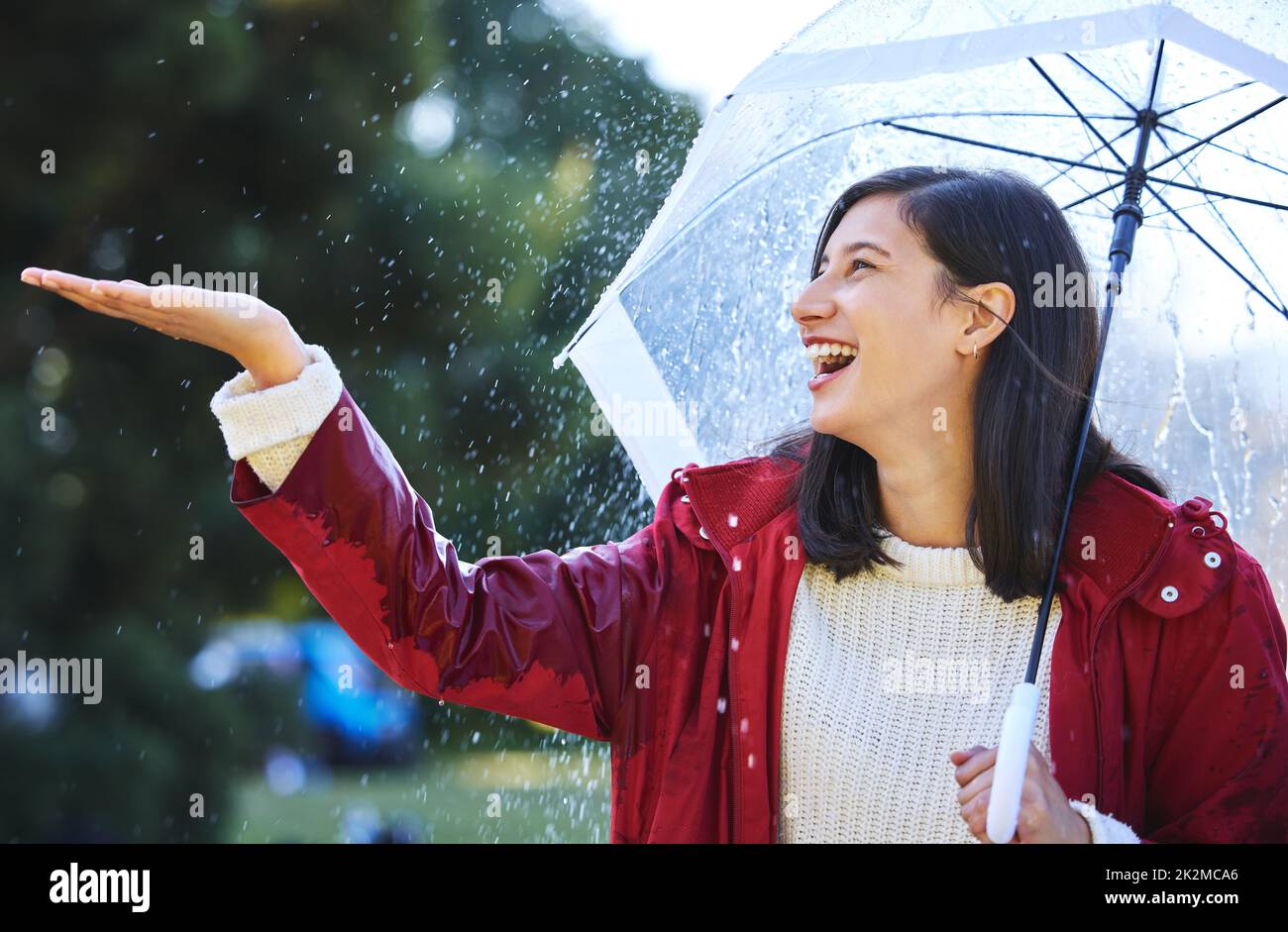 Its raining down hard. Shot of a young woman standing in the rain with ...