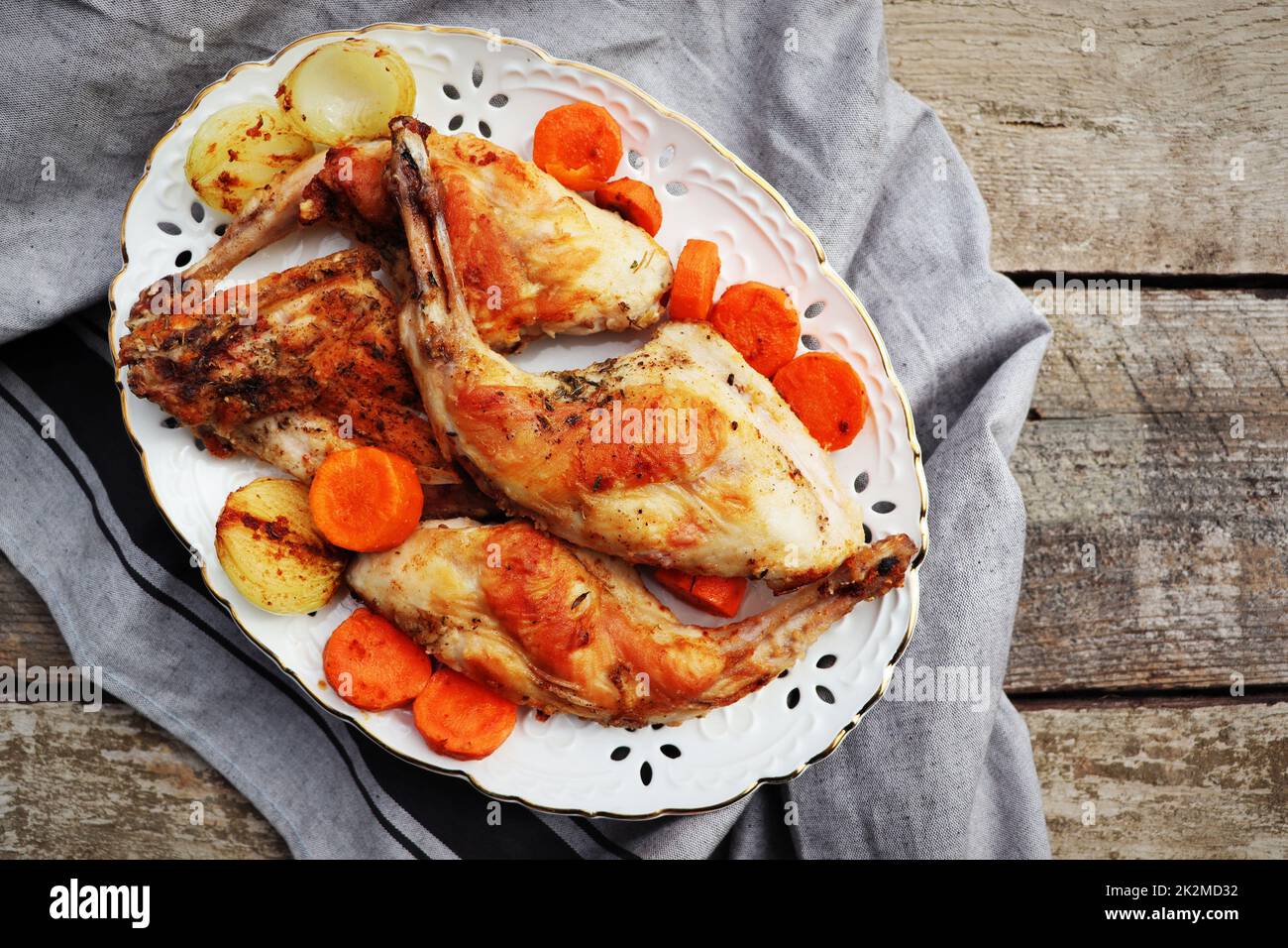 Roasted Rabbit Haunches on white plate with Stewed Vegetables on Rustic ...