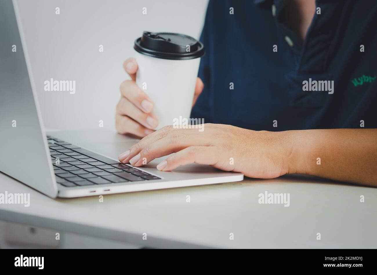 man using computer laptop and coffee cup paper searching internet, sending sms, using text ...