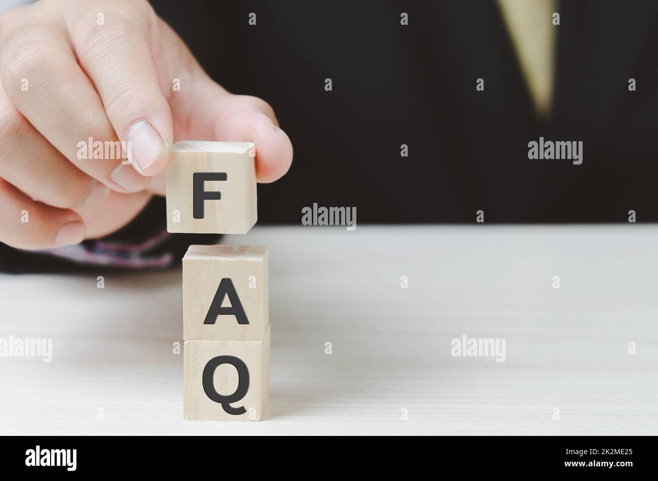 Hand put wooden cubes with FAQ frequently asked questions on table and ...