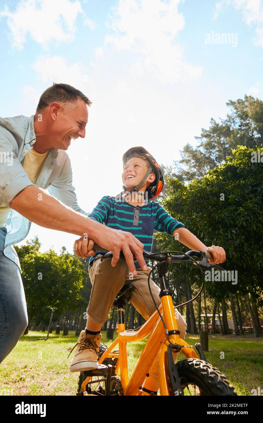 Dads got you. Shot of a father teaching his son how to ride a bicycle ...