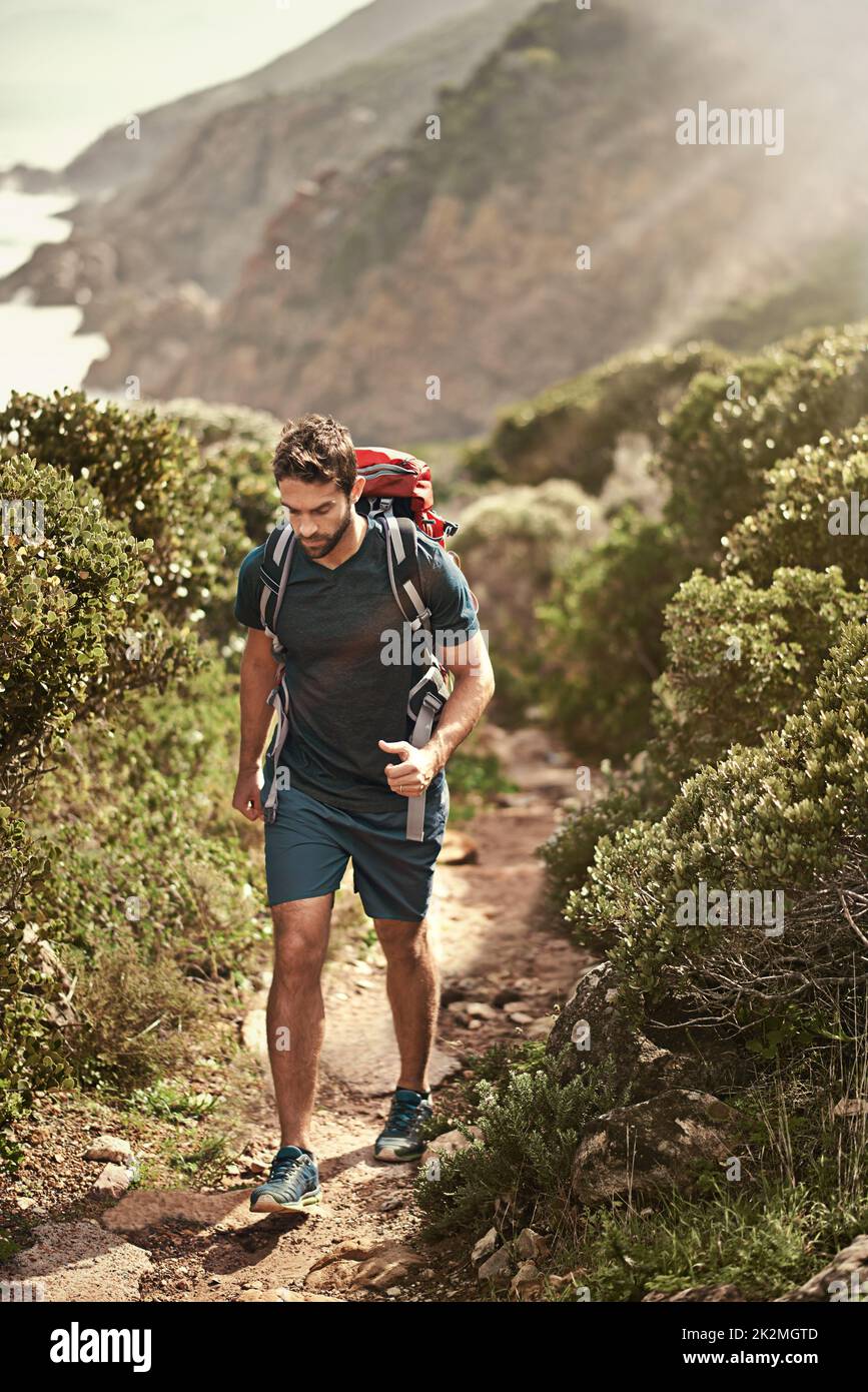 Nothing beats a weekend hike. a young man hiking along a mountain trail ...