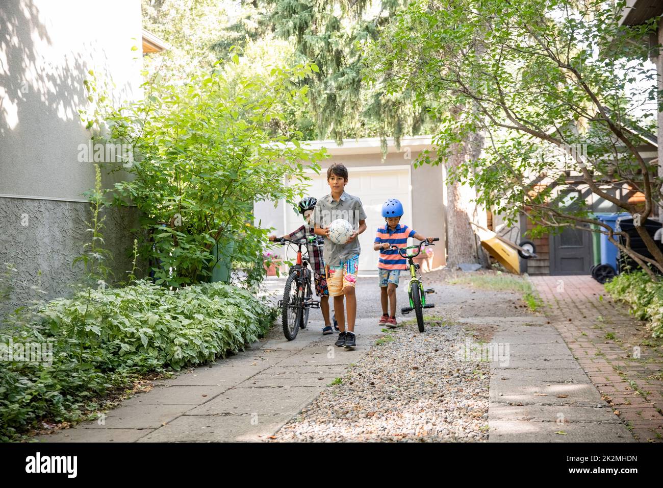 Boys with ball and bicycles walking on pavement Stock Photo - Alamy