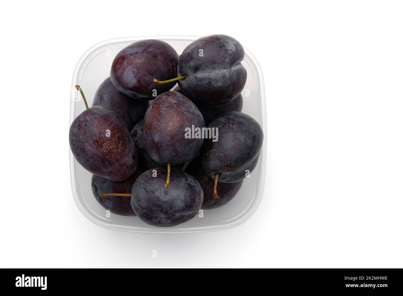 fresh ripe purple plums in plastic food box isolated on white ...