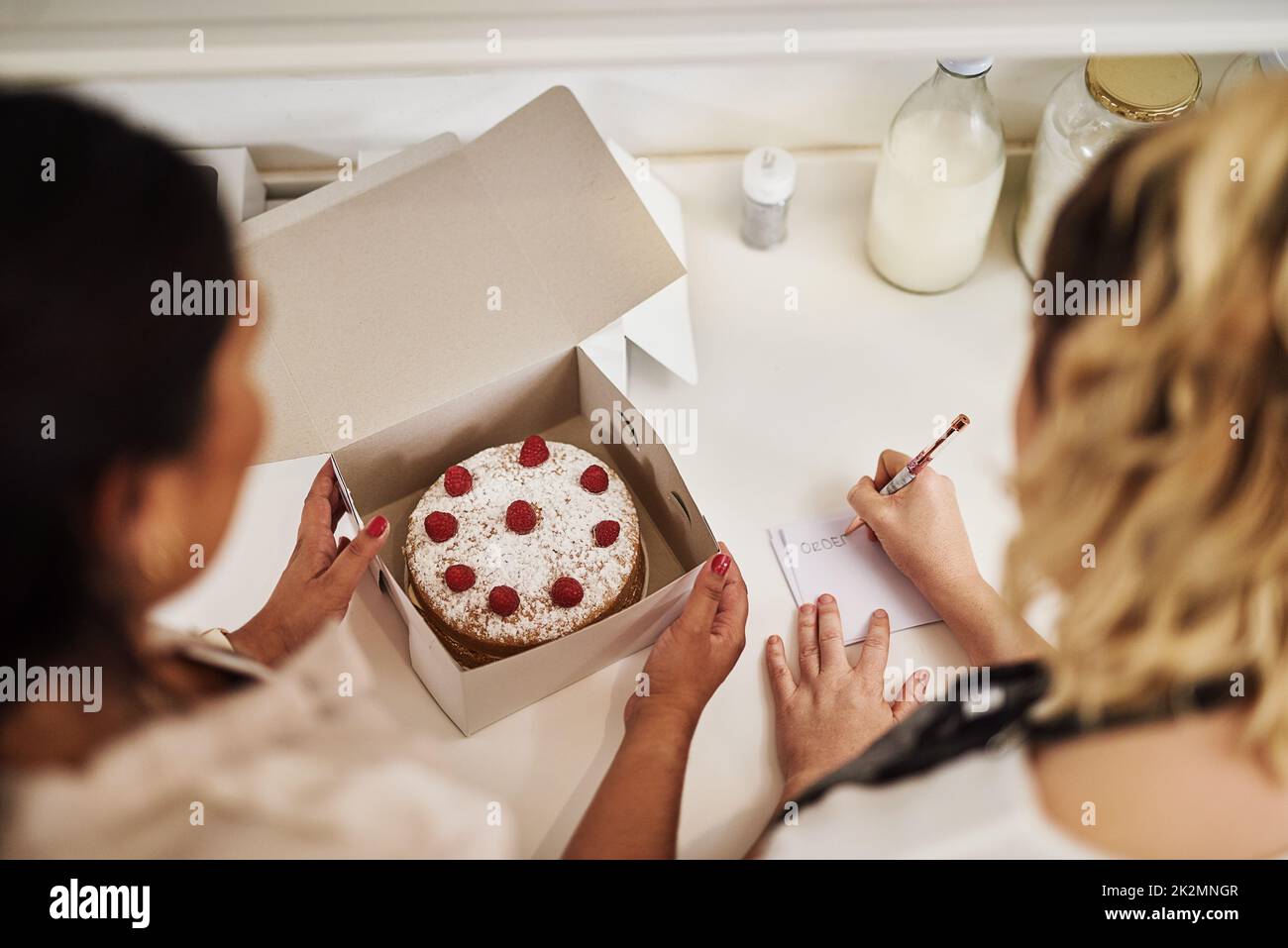 Our cakes are to die for. Cropped shot of two bakers preparing a cake ...