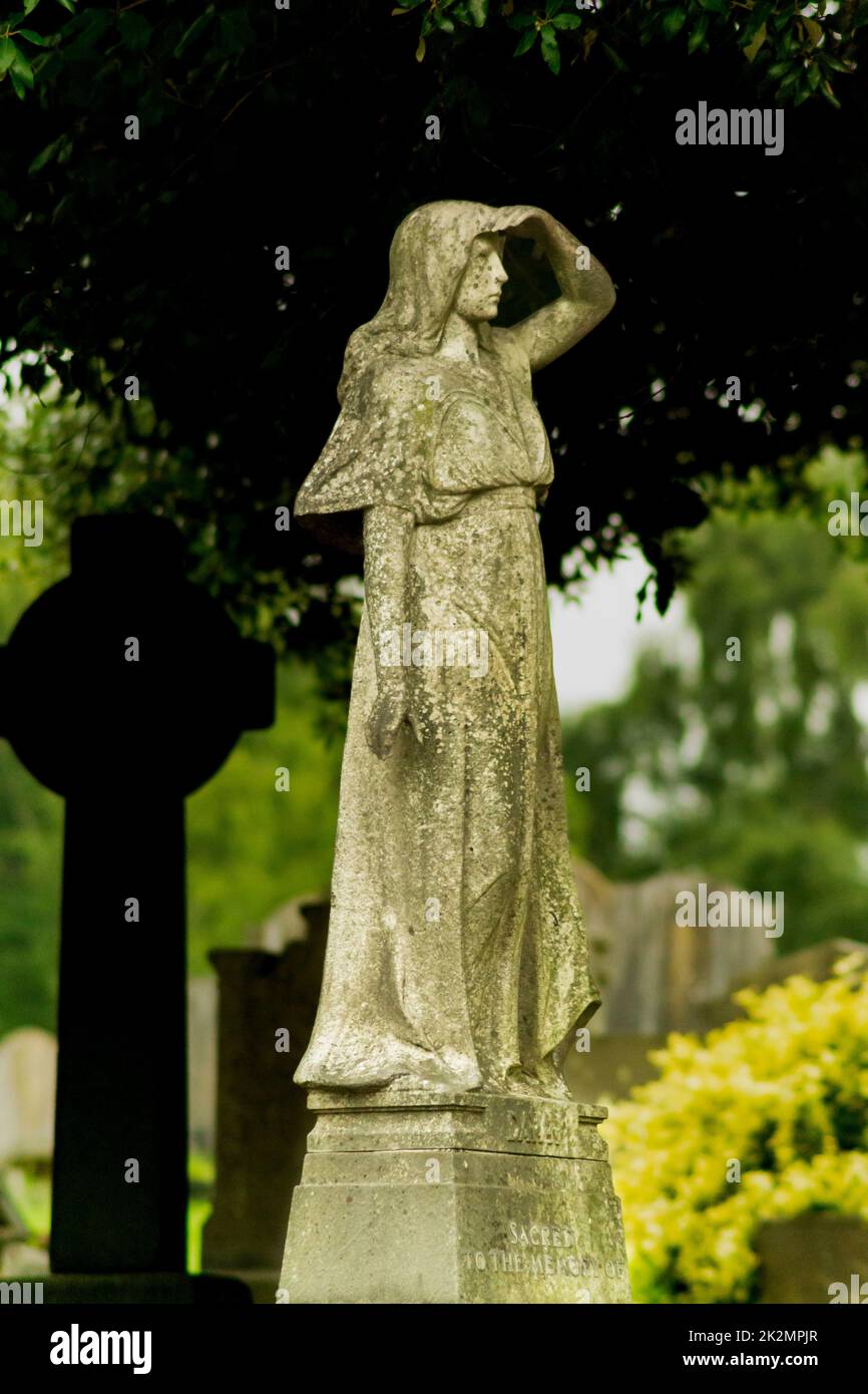 Memorial statue in a graveyard with hand shading her eyes Stock Photo ...