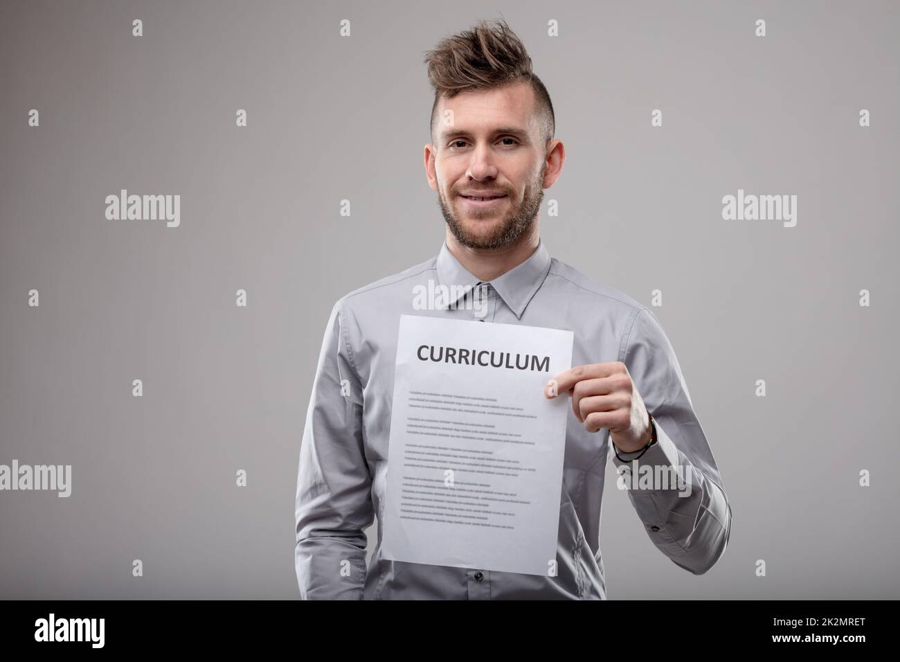Trendy modern bearded young man holding up a typed Curriculum Stock ...