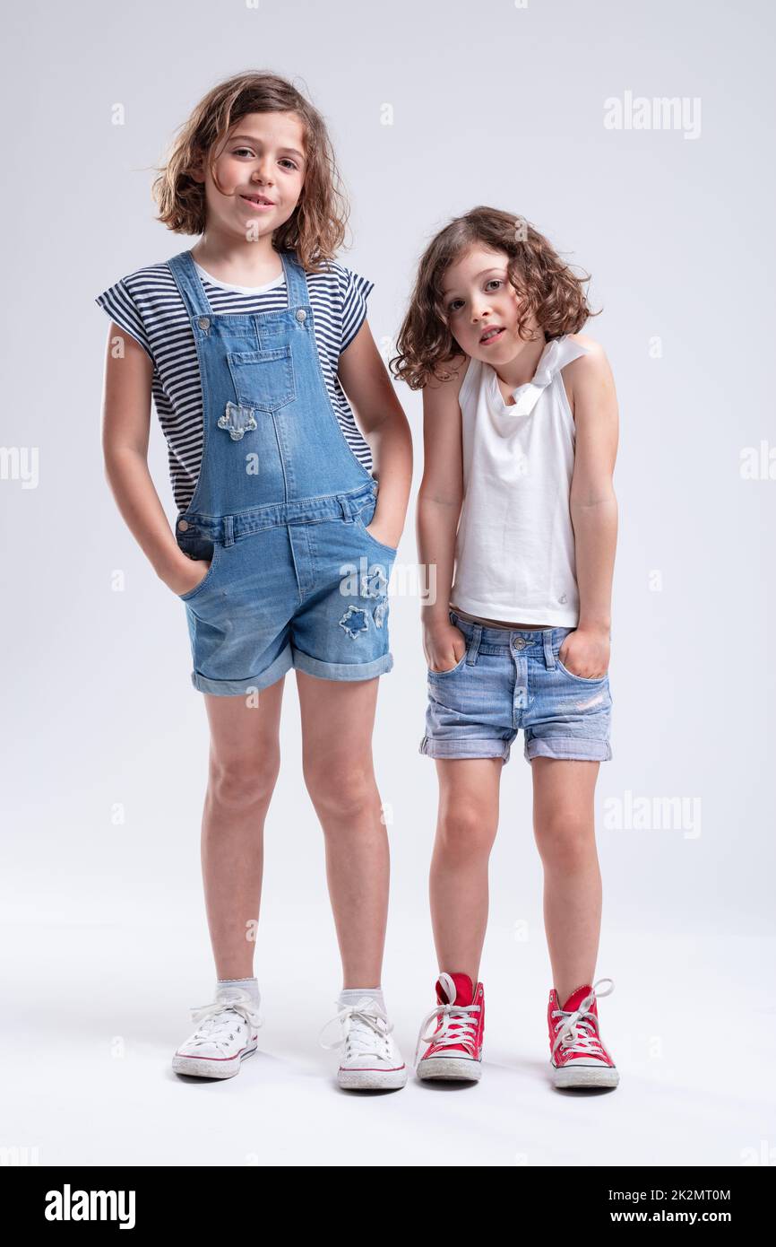 Two young sisters standing with hands in pockets Stock Photo - Alamy