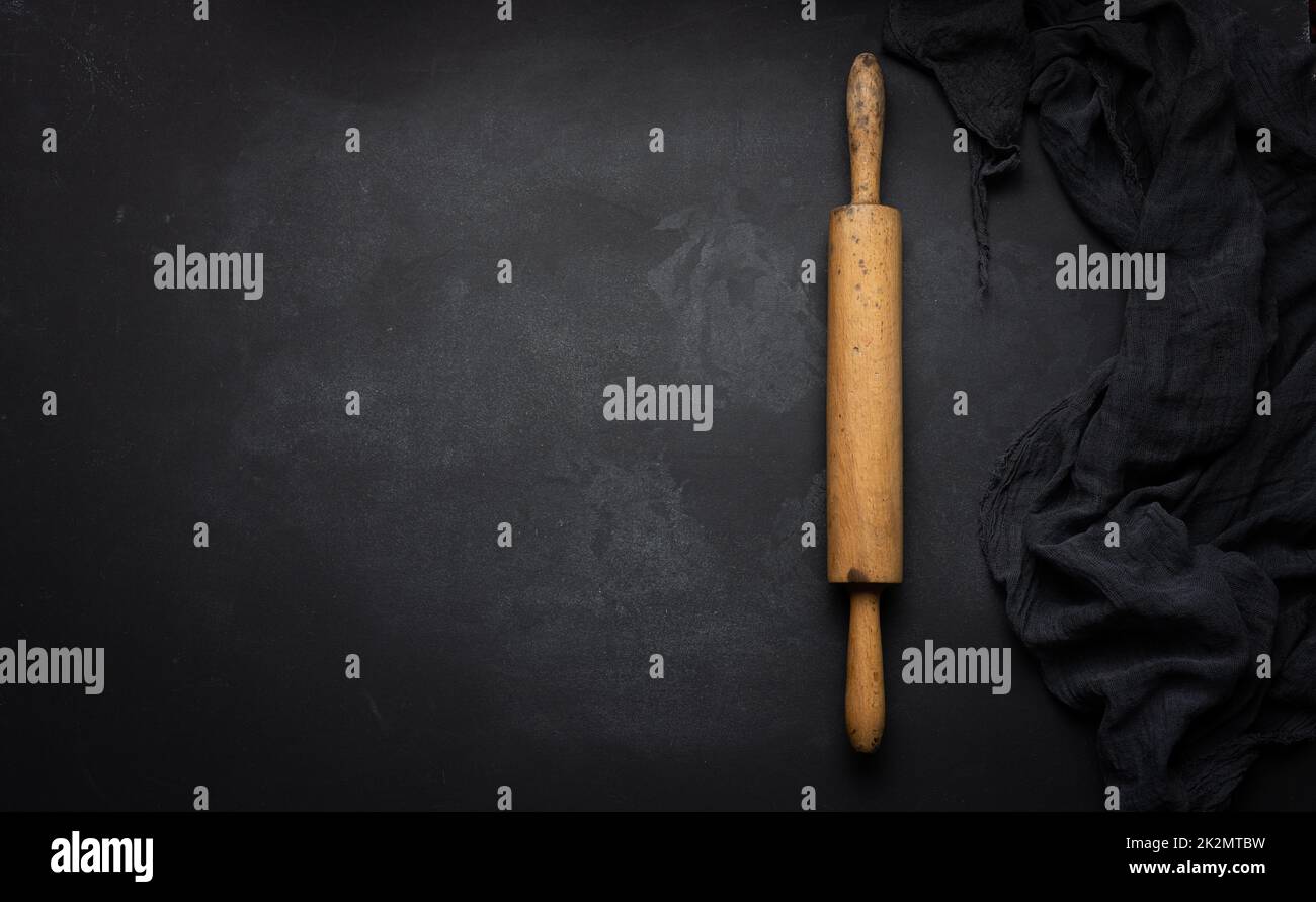 Old wooden rolling pin for rolling dough on a black background, top ...