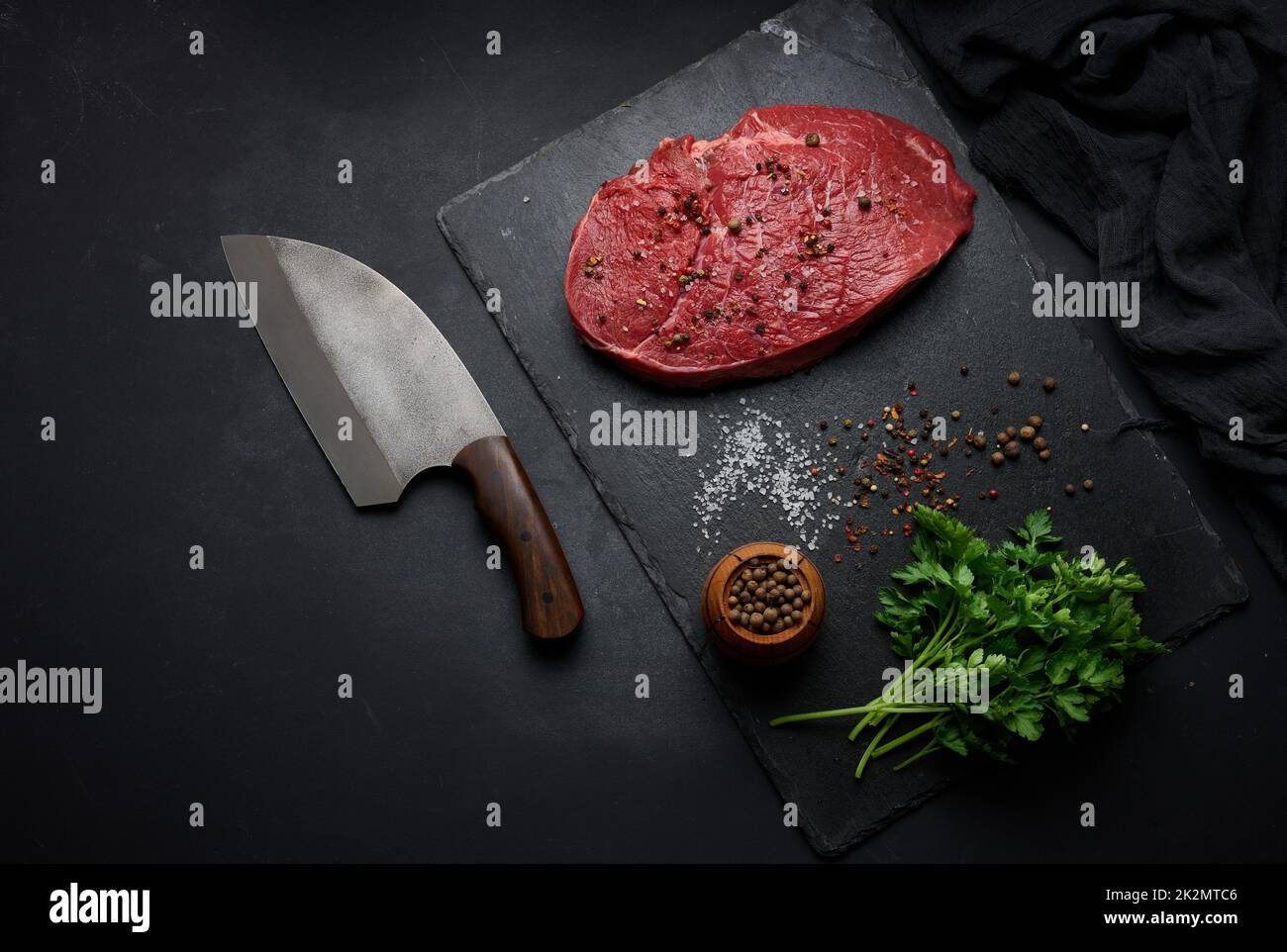 Raw beef tenderloin lies on a cutting board and spices for cooking on a ...