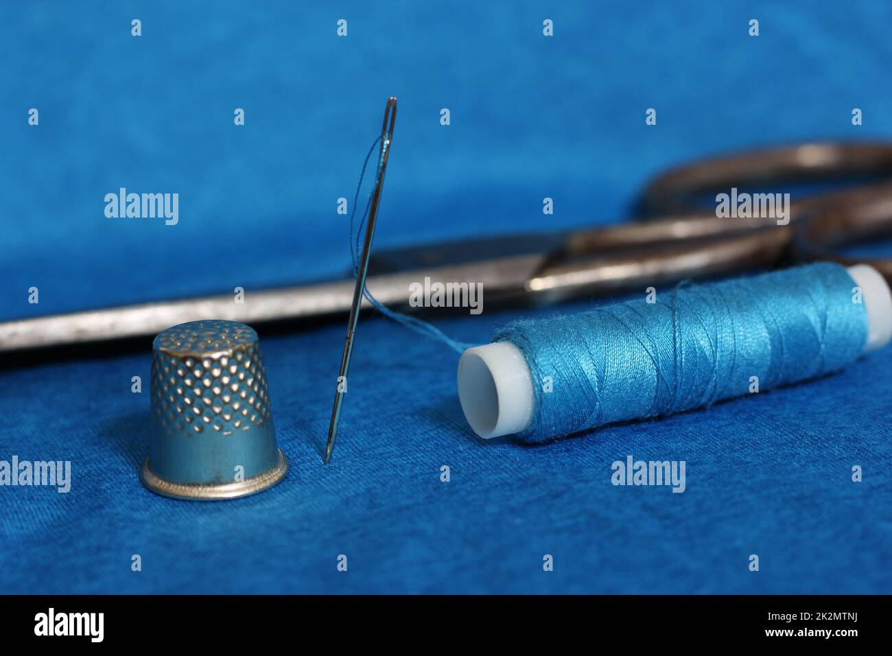 Spool of Blue Thread, Thimble and Needle on Blue Fabric Stock Photo - Alamy