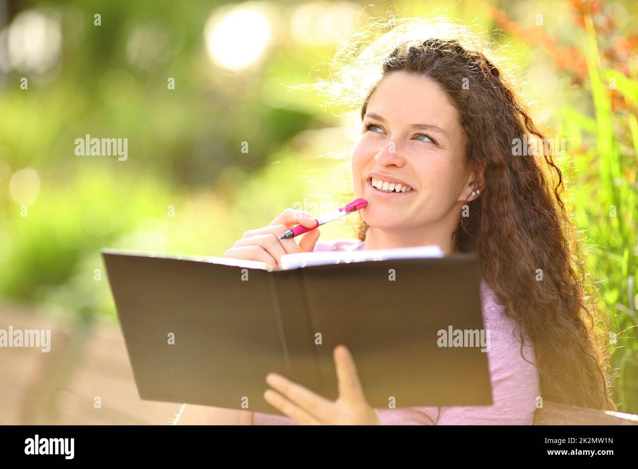 Woman thinking ready to write in a notebook Stock Photo - Alamy