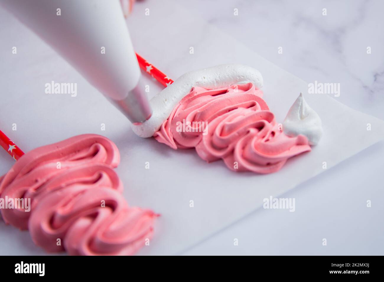 On light parchment there are pink meringue caps on sticks, the cook ...