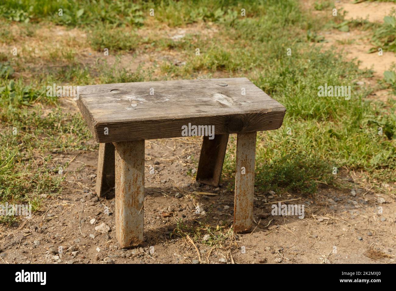 Old homemade wooden stool with metal legs. A small stool standing on ...