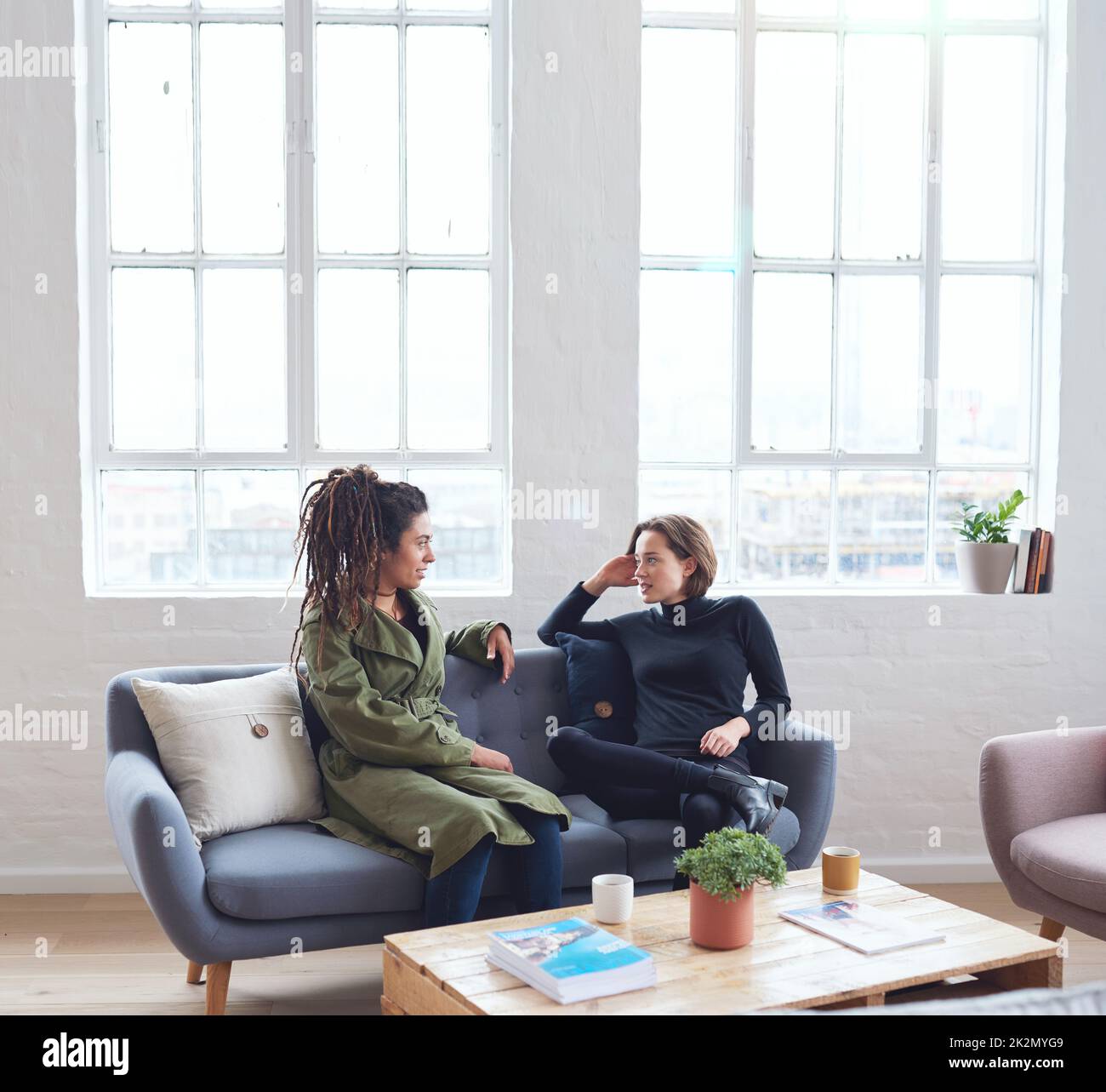 Creative women on sofa talking, having conversation or being social in ...