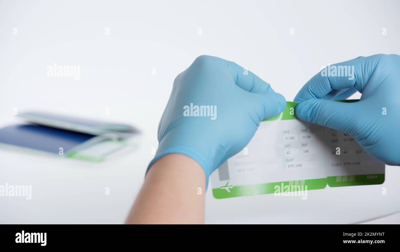 cropped view of man in latex gloves tearing boarding pass near blurred ...