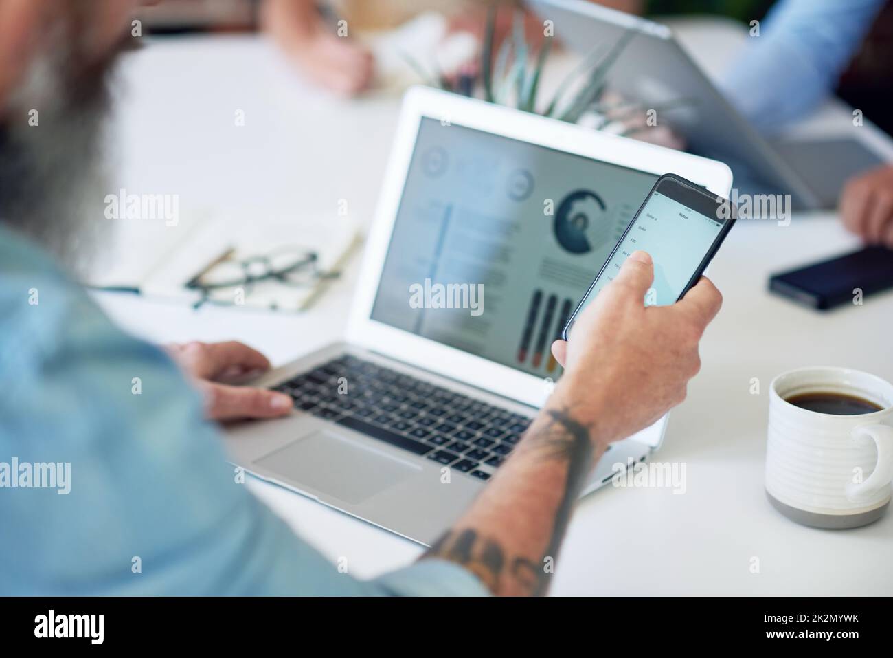 businessman using smartphone working on laptop computer with financial ...