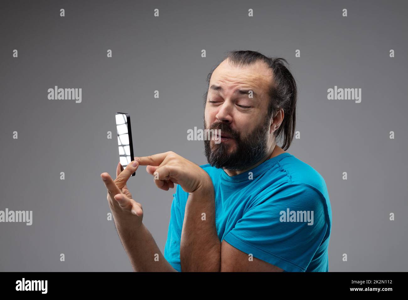 Man with squeamish grimace poking phone screen Stock Photo - Alamy