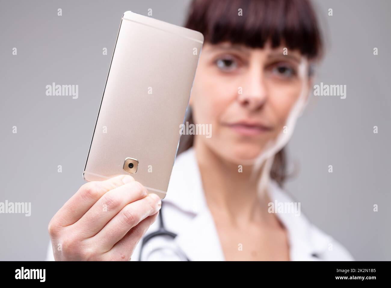 Female doctor holding up a mobile phone Stock Photo - Alamy